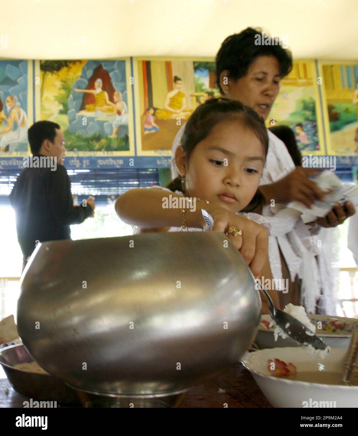 A Cambodian girl offers food to the Buddhist monk during Pchum Ben, or ...