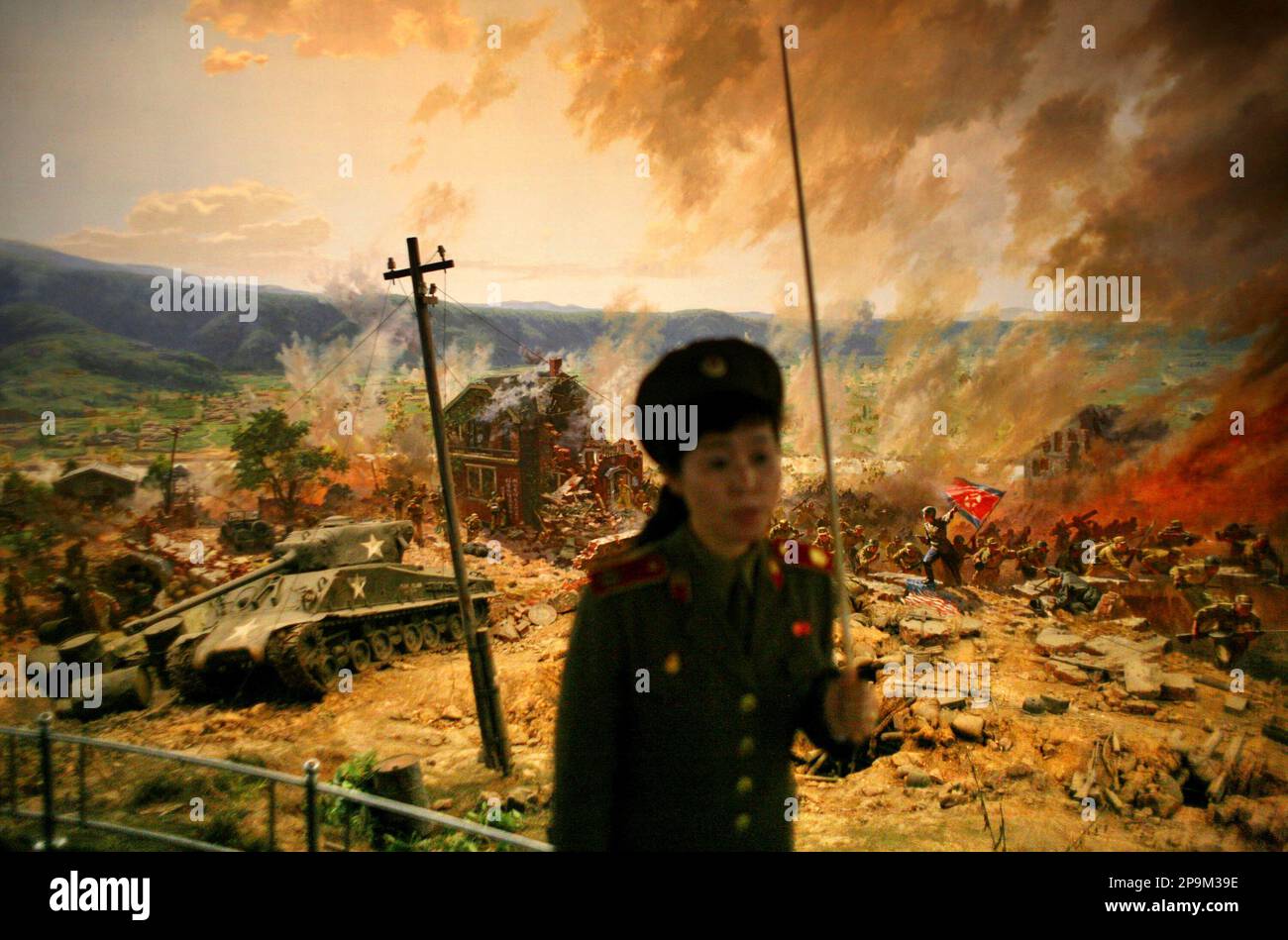 A guide gives a lecture in front of a diorama showing the Korean War's ...