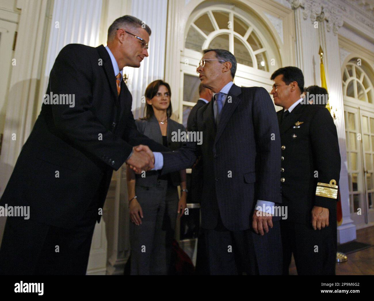Colombian President Alvaro Uribe, center, shake hands with Keith ...