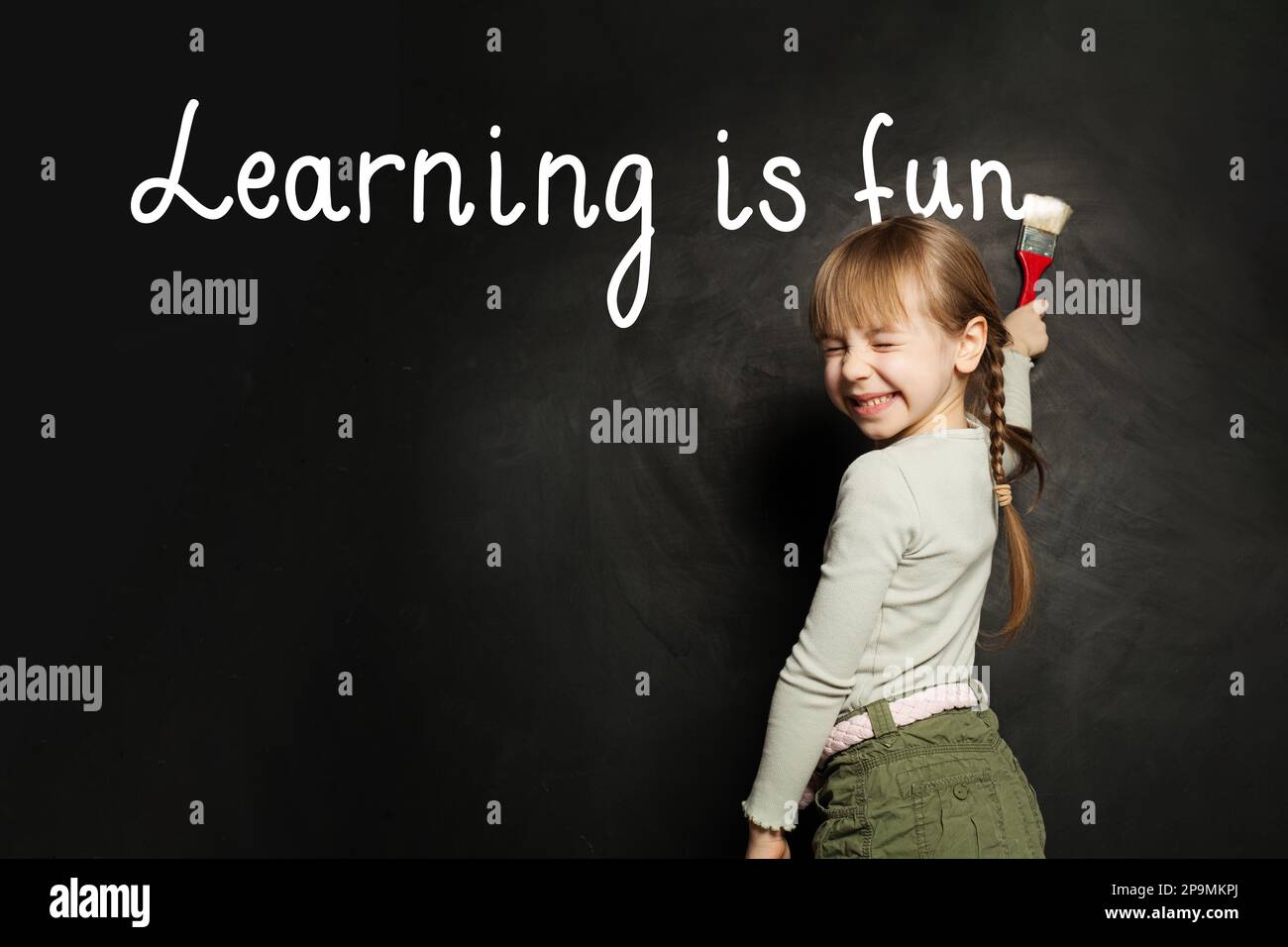 School child girl writing on the blackboard with chalk. Learning is fun ...
