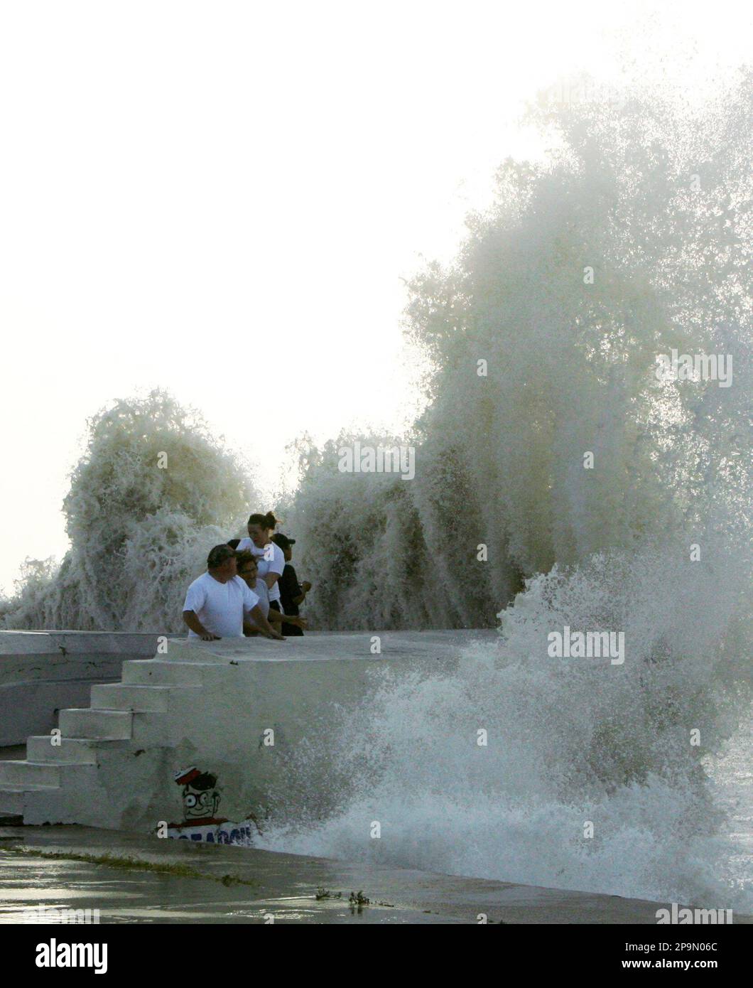 People pull back as a wave crashes against the seawall as Hurricane Ike ...