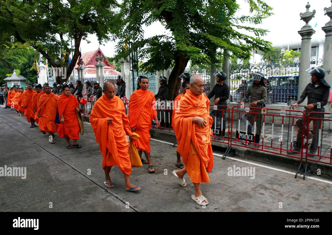 Buddhist monks walk in front of riot-police officers standing guard in ...