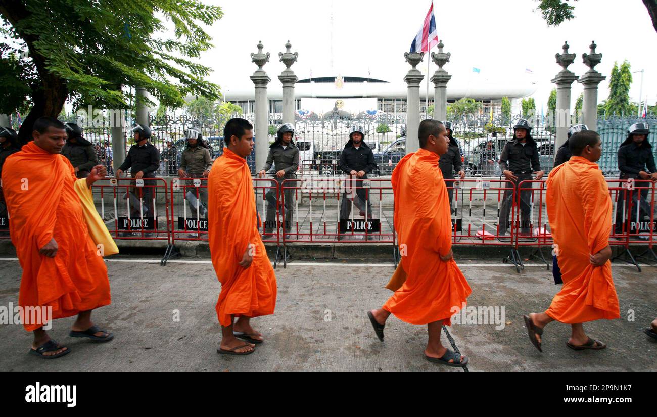 Buddhist monks walk in front of riot-police officers standing guard in ...