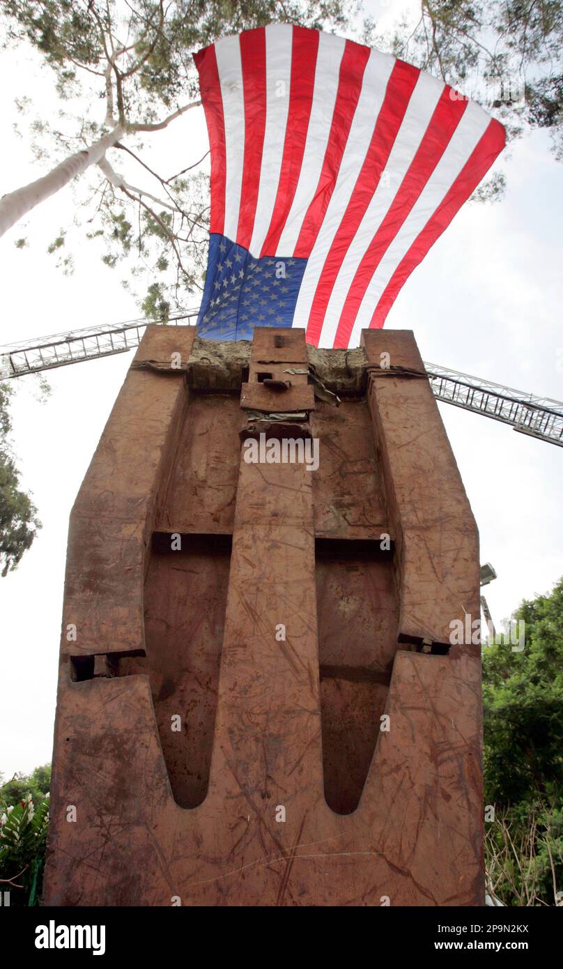 Supported by fire department aerial ladders, a giant American flag ...