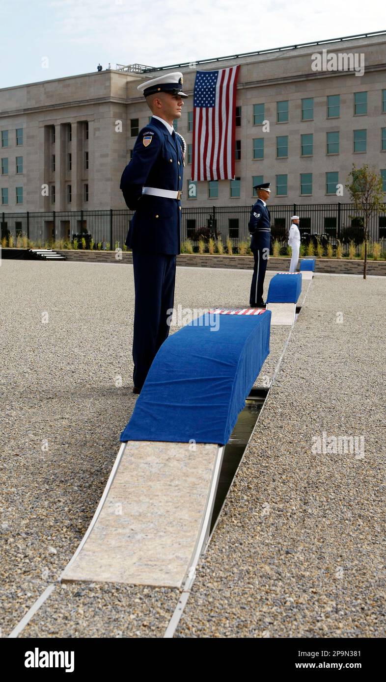 Military personnel stand ready to remove the covers of the individual ...
