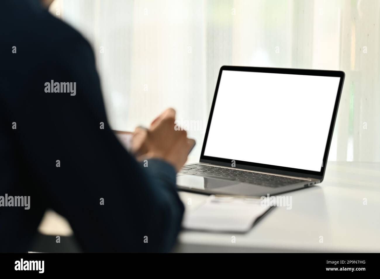 Back view of man worker sitting at office desk with blank screen laptop ...