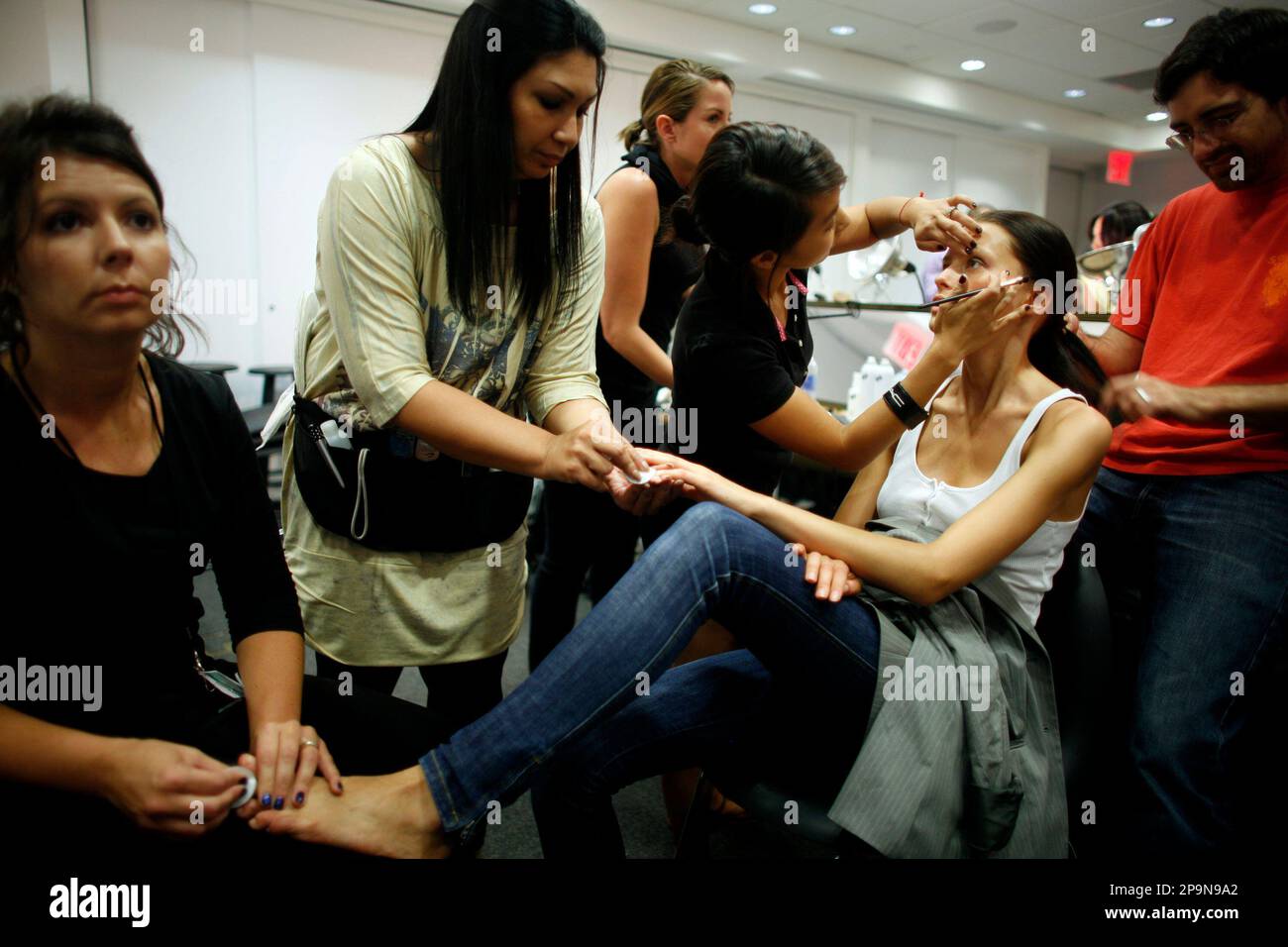 A model who arrived late has her hair, makeup, fingernails and toes ...