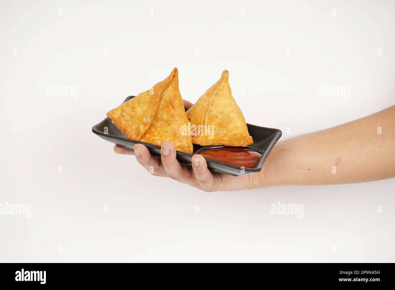 Samosa plate in hand isolated on white background Stock Photo - Alamy