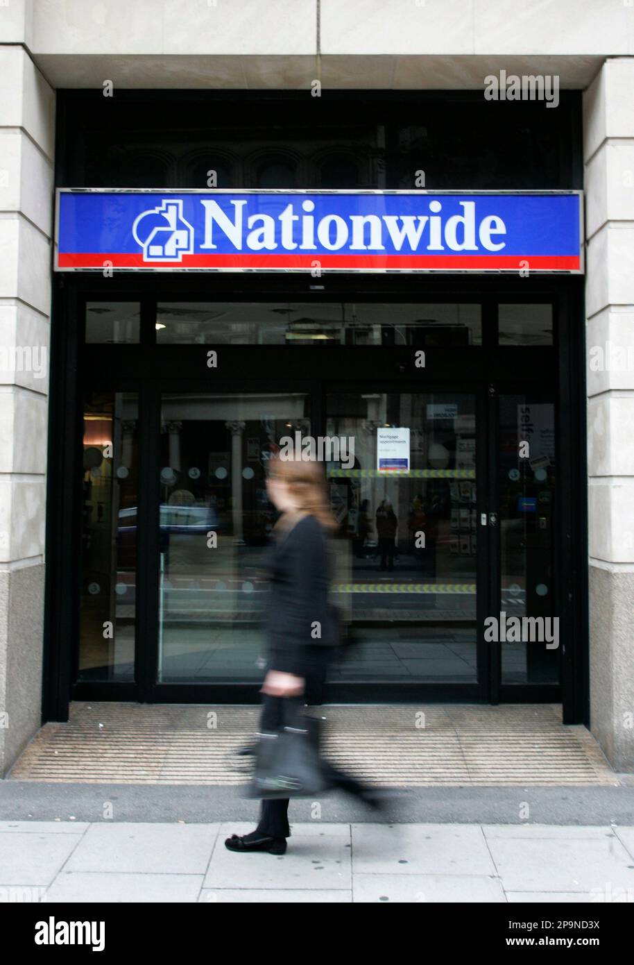 A woman walks by a branch of Nationwide Building Society in London ...