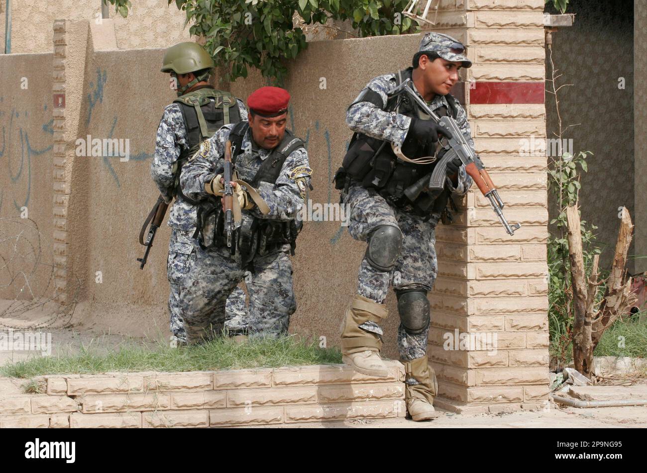 Iraqi policemen are seen, as they search a home in the Dora ...