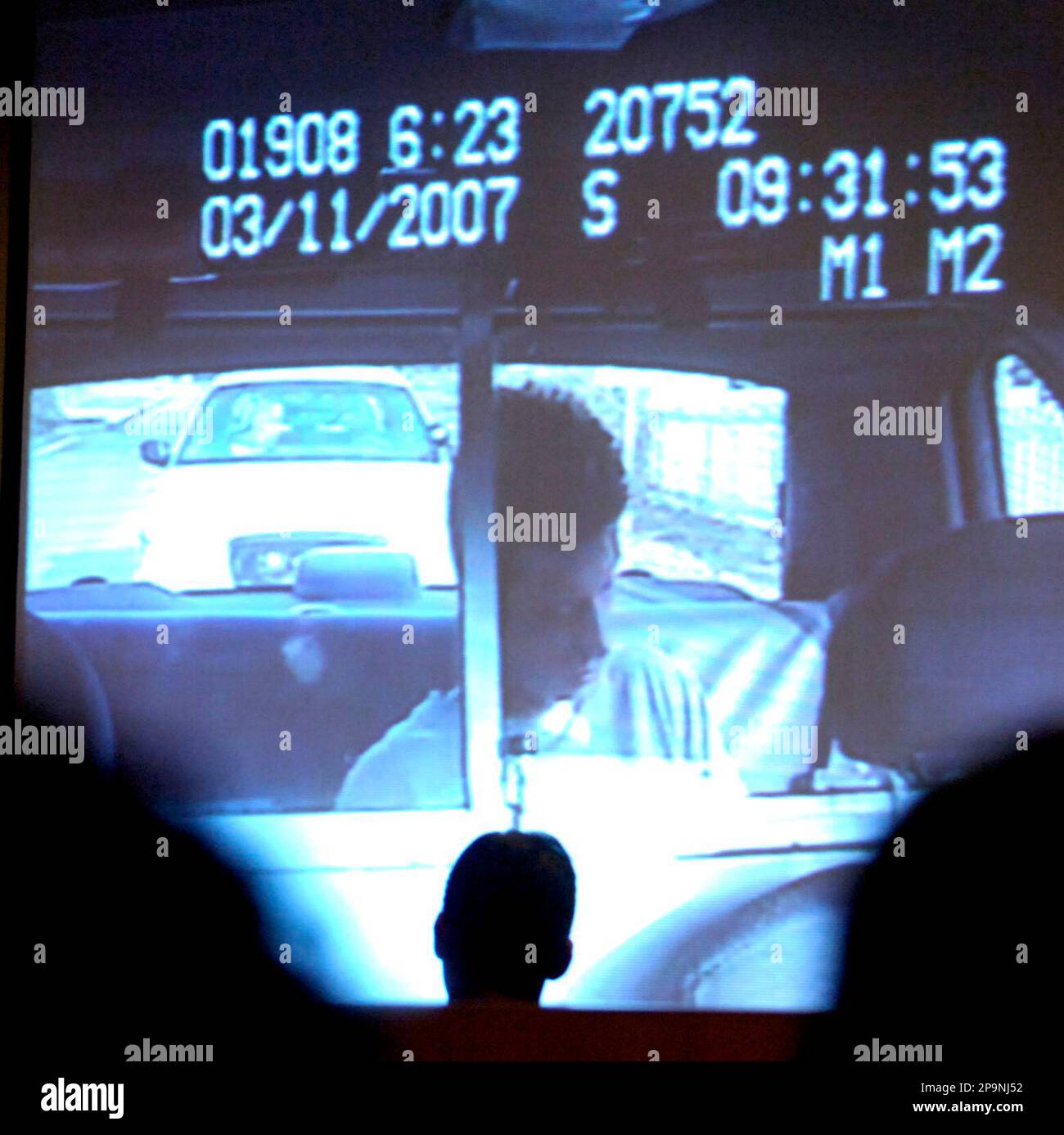 Eric McLean, back of head in bottom center of frame, watches a police ...