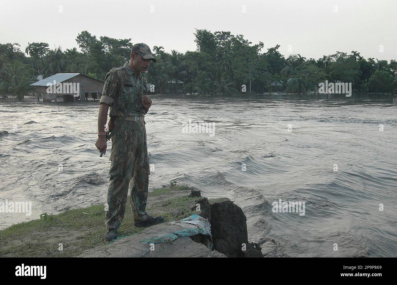 A Central Reserve Police soldier looks at a broken embankment in ...