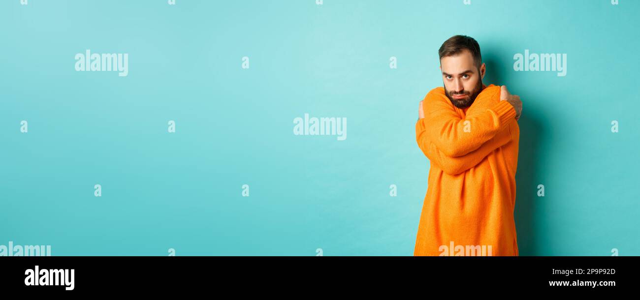 Timid man feeling offended and defensive, hugging himself and looking ...