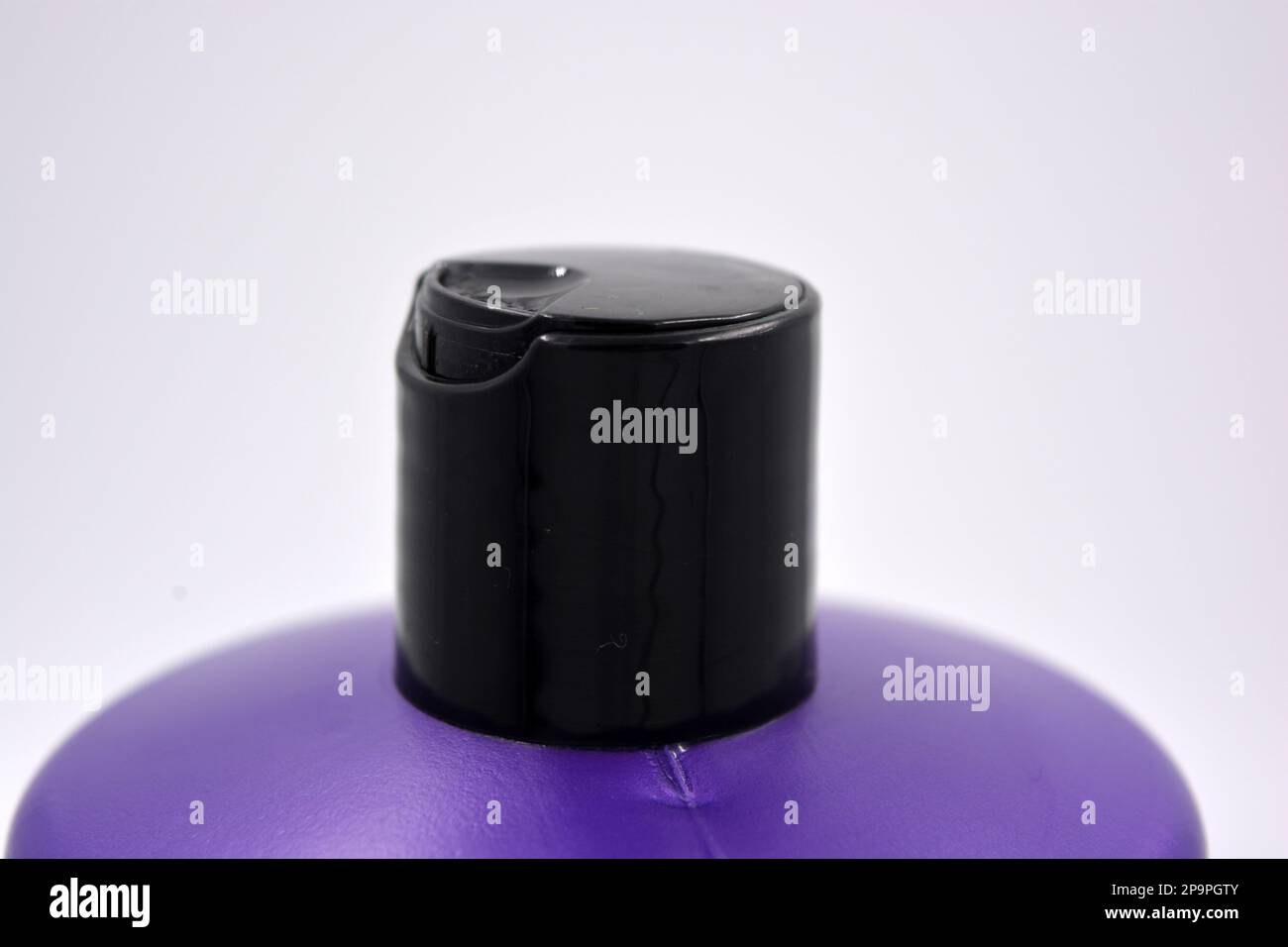 A large purple plastic round shampoo bottle with a black lid located on ...