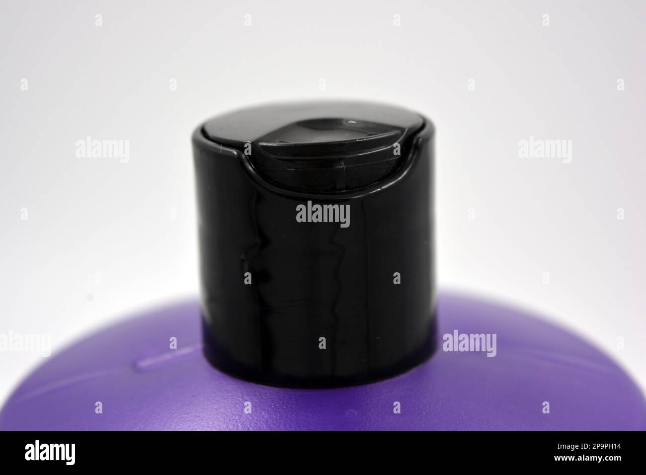 A large purple plastic round shampoo bottle with a black lid located on ...