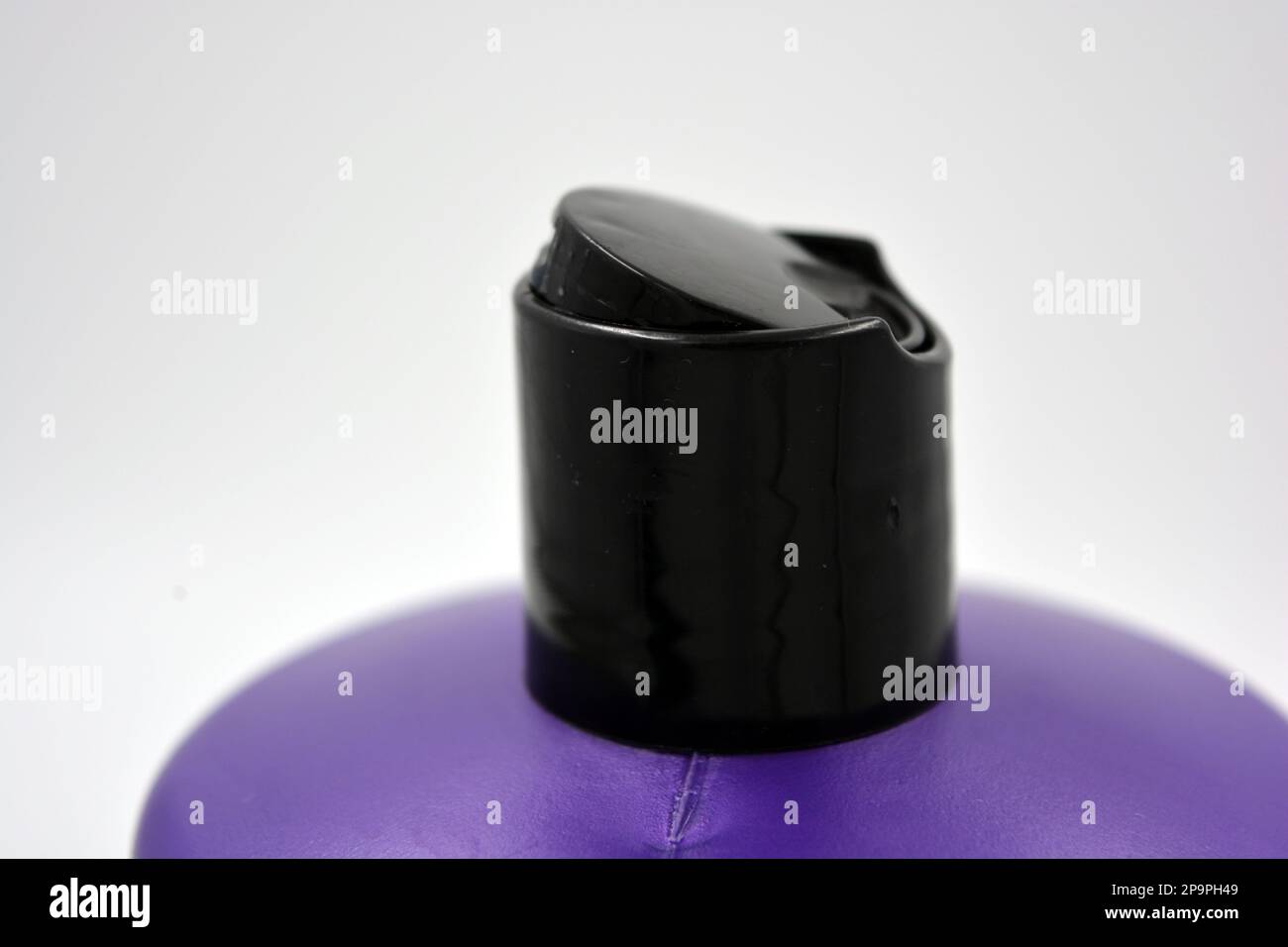 A large purple plastic round shampoo bottle with a black lid located on ...