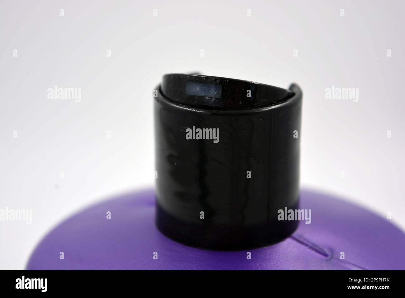 A large purple plastic round shampoo bottle with a black lid located on ...