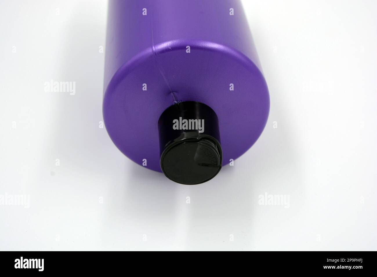 A large purple plastic round shampoo bottle with a black lid located on ...