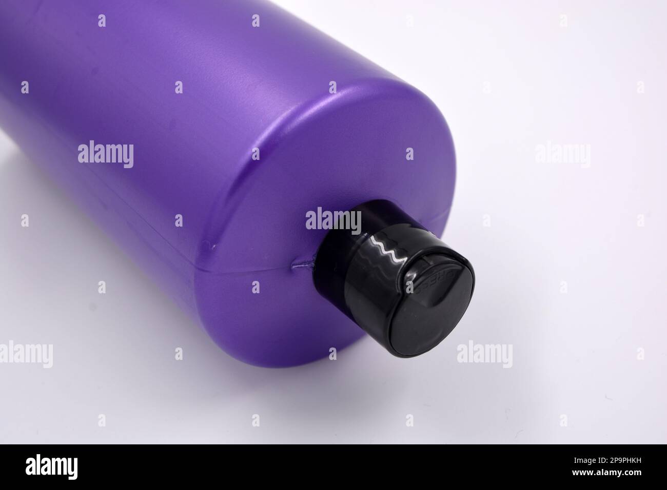 A large purple plastic round shampoo bottle with a black lid located on ...