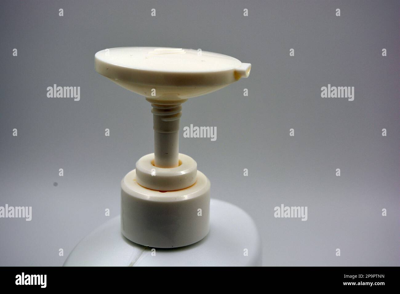 A large white plastic bottle with a large dispenser for cosmetics ...