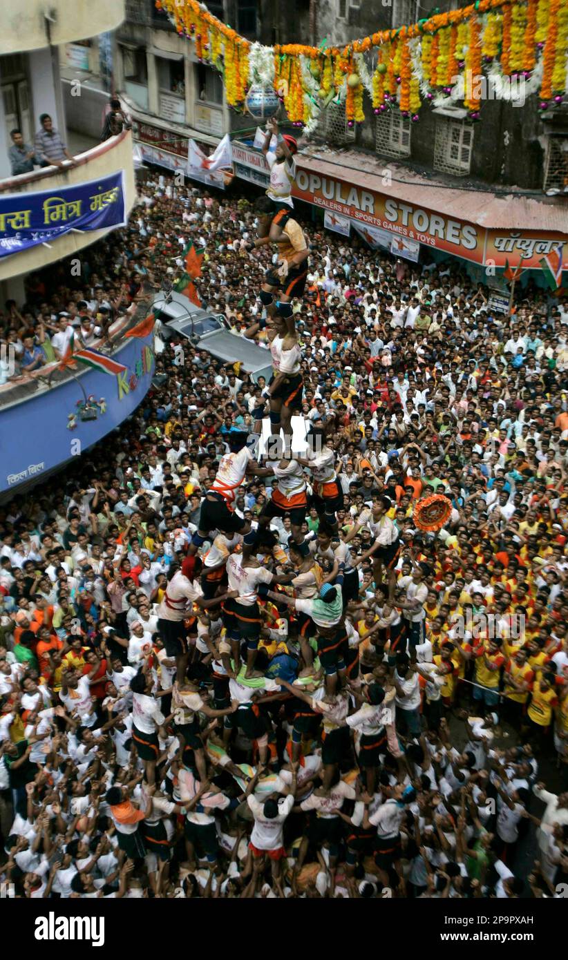 Hindu devotees try to form a human pyramid to break an earthen pot ...