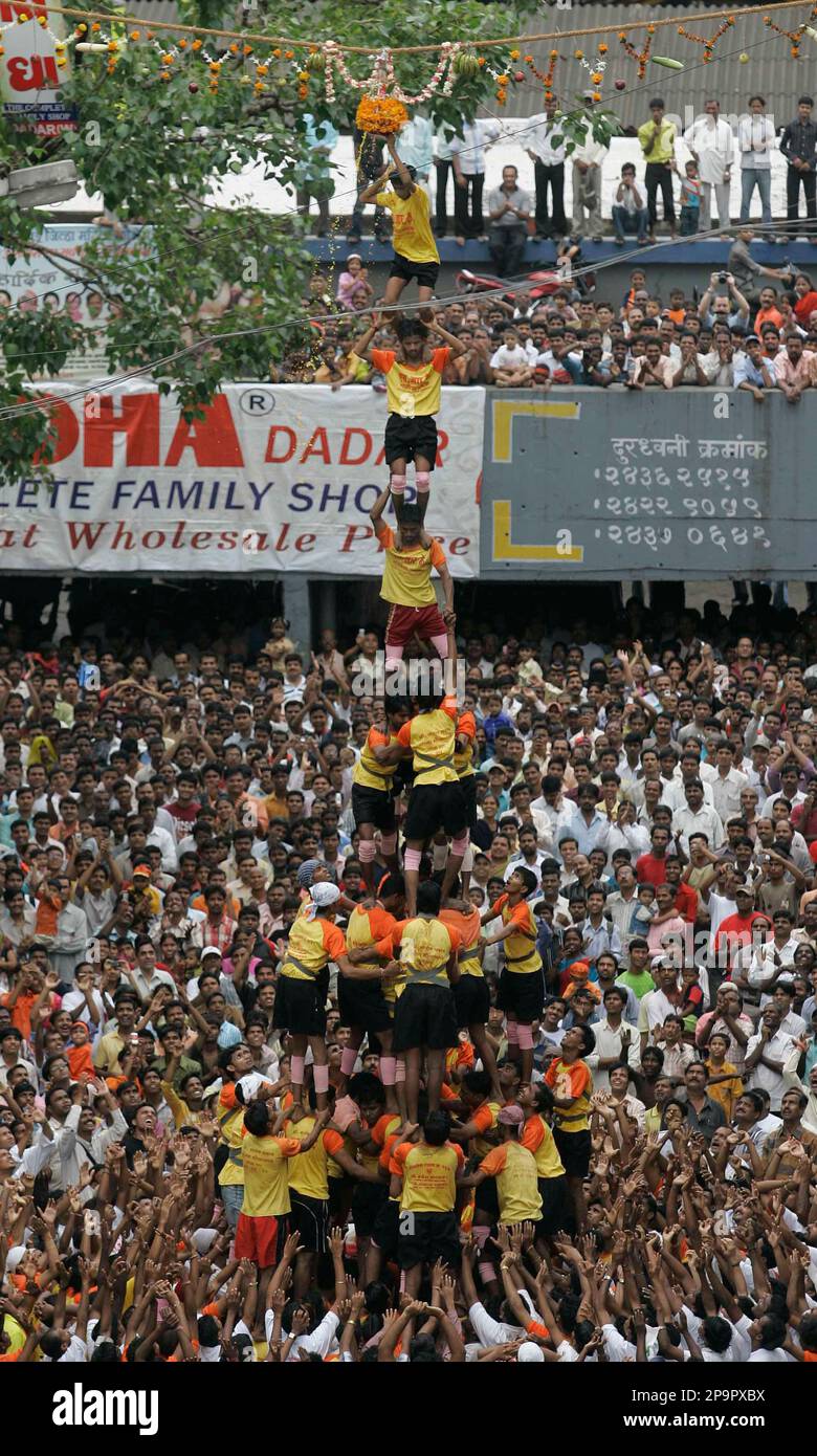 Hindu devotees try to form a human pyramid to break an earthen pot ...