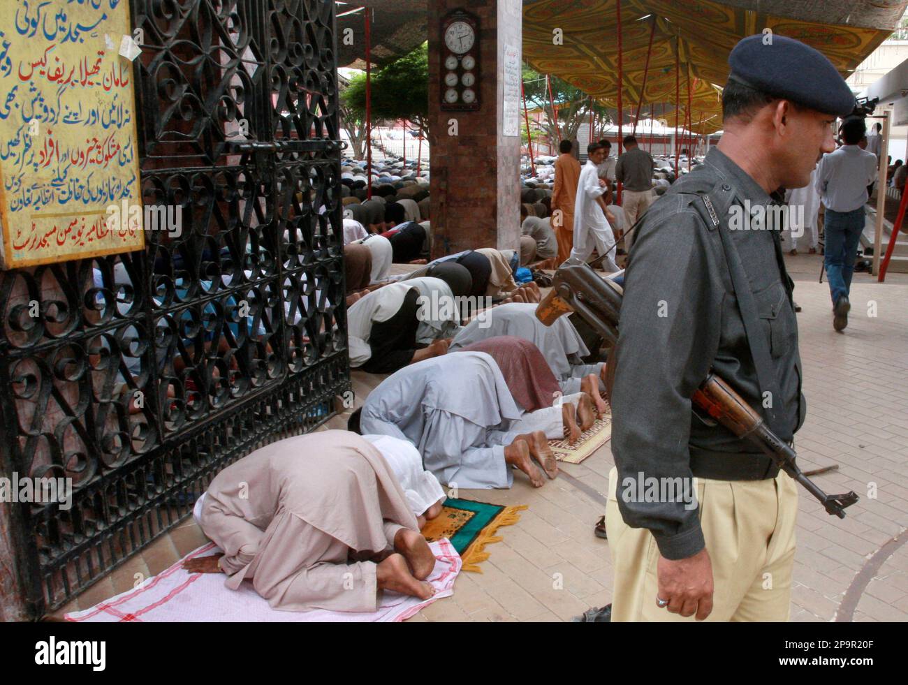 A Pakistani police officer stands guard as people offering Friday ...