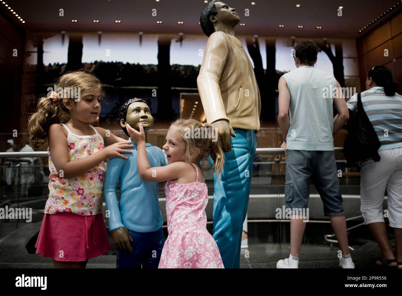 Cousins Oliva Philips, 4, and Mia Lucente, 7, play with a statue, while ...