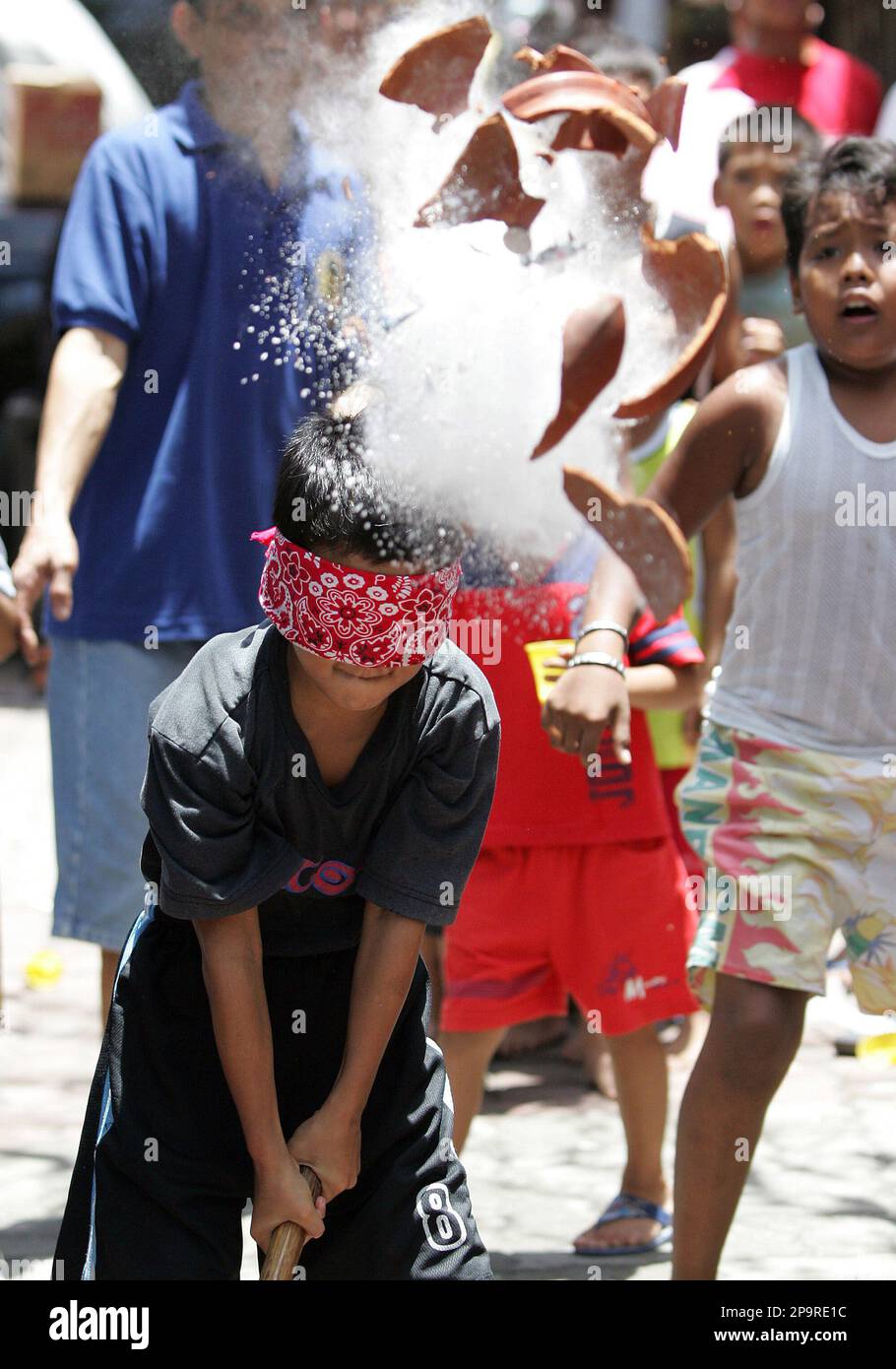 A Filipino child hits the clay pot during games to celebrate the feast ...