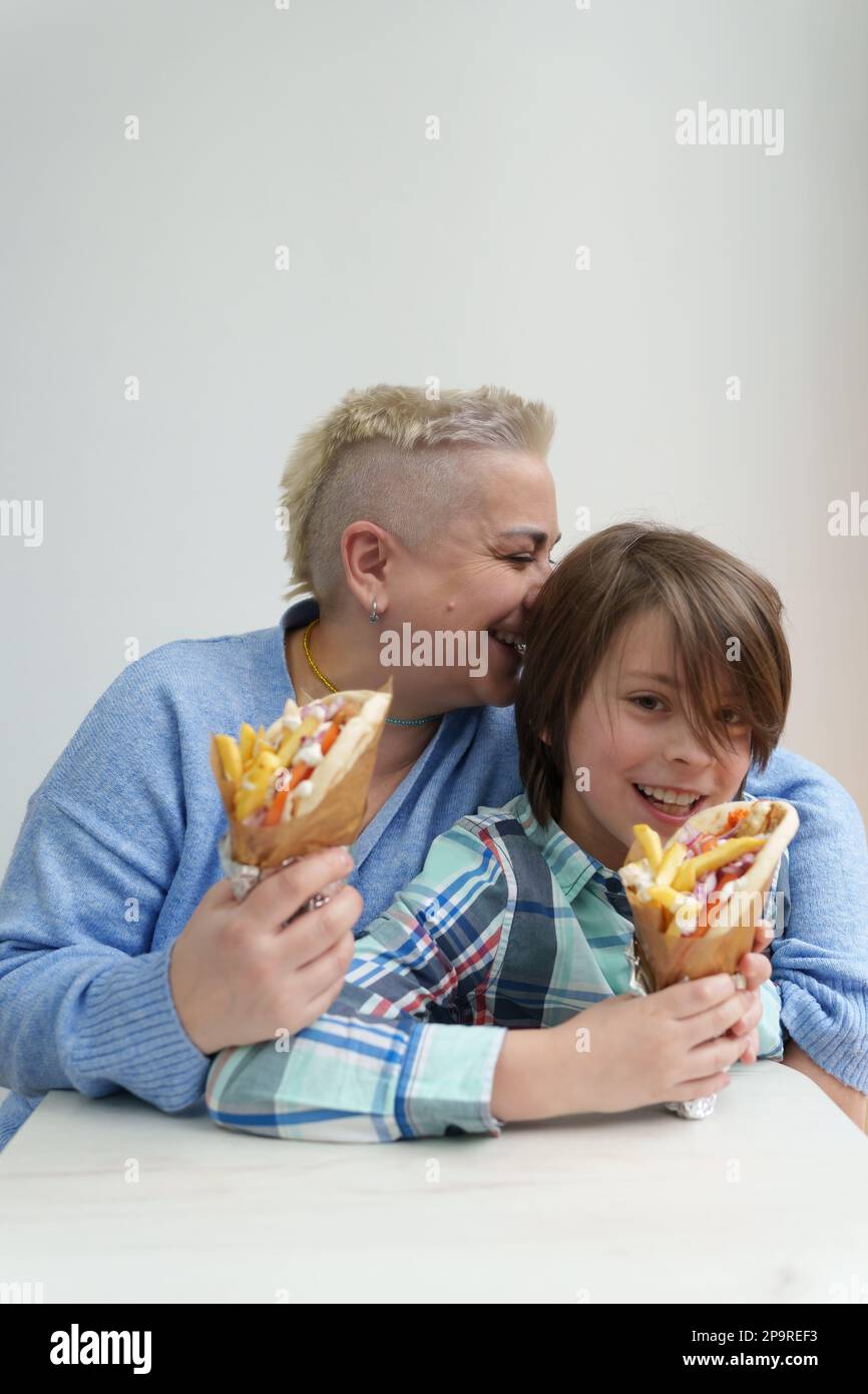 Happy mother cuddling with her son while eating gyros in Greek ...