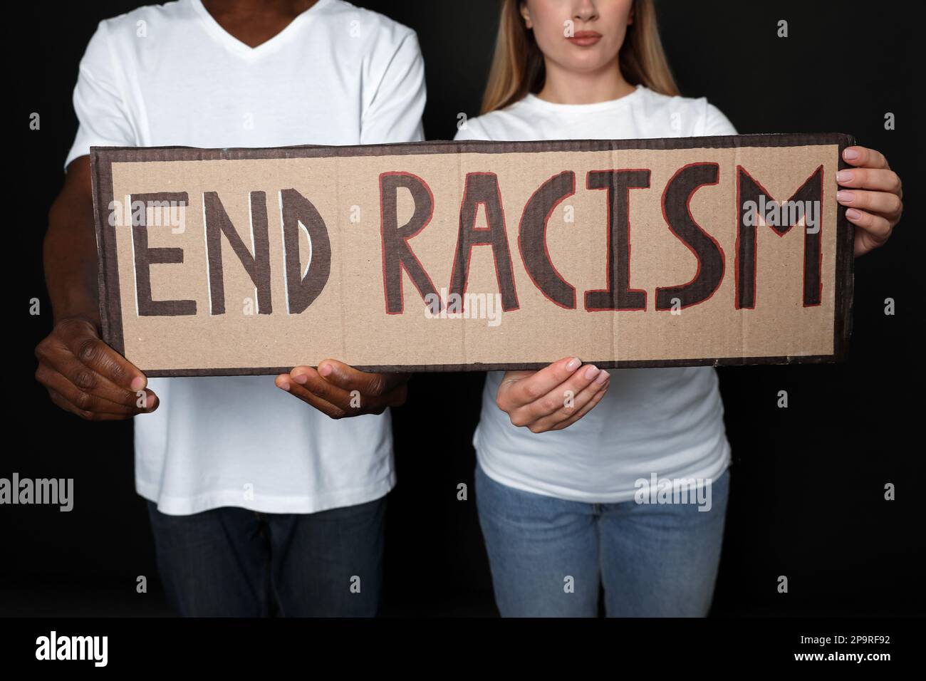 Young woman and African American man holding sign with phrase End ...