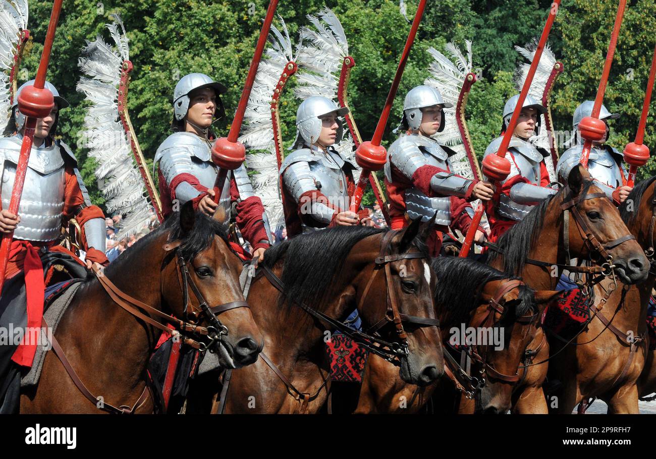 Actors dressed in Polish army historical costumes ride on horses during ...