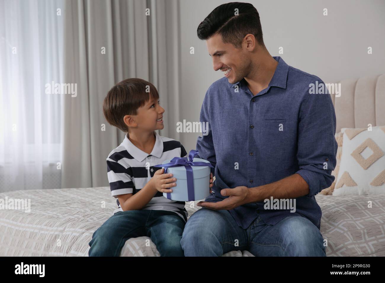 Man receiving gift for Father's Day from his son at home Stock Photo ...