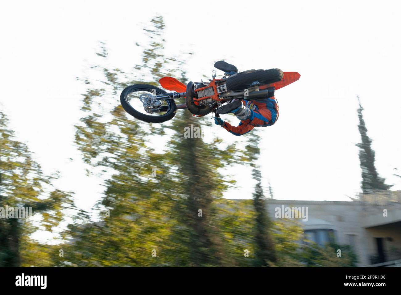 Motocross MX Freestyle jump at tree tops level on a city street Stock ...