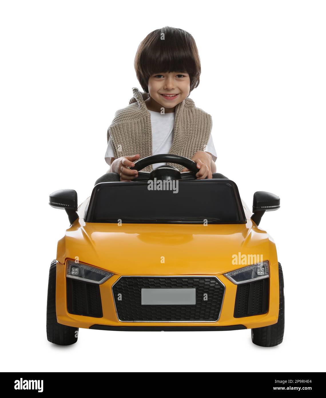 Cute little boy driving children's electric toy car on white background ...