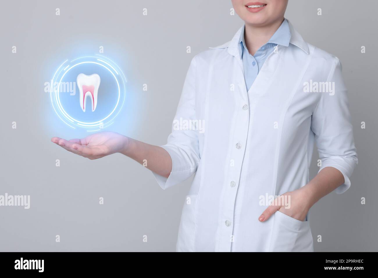 Dentist showing virtual model of tooth on light grey background ...