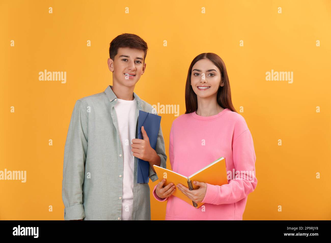 Teenage students with stationery on yellow background Stock Photo - Alamy