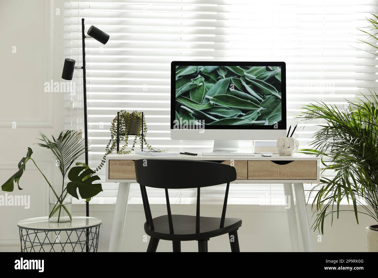 Comfortable workplace with modern computer and green plants in room ...