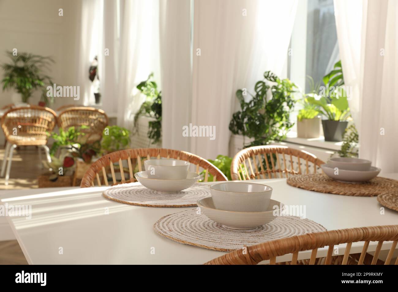 Stylish dining table and wicker chairs near window in room. Interior ...