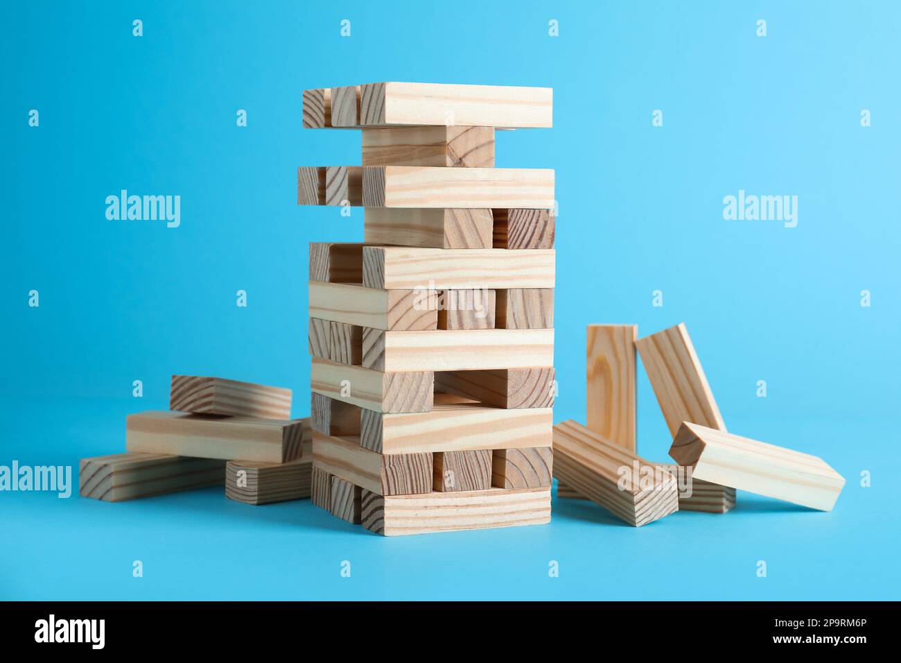 Jenga tower made of wooden blocks on light blue background Stock Photo ...
