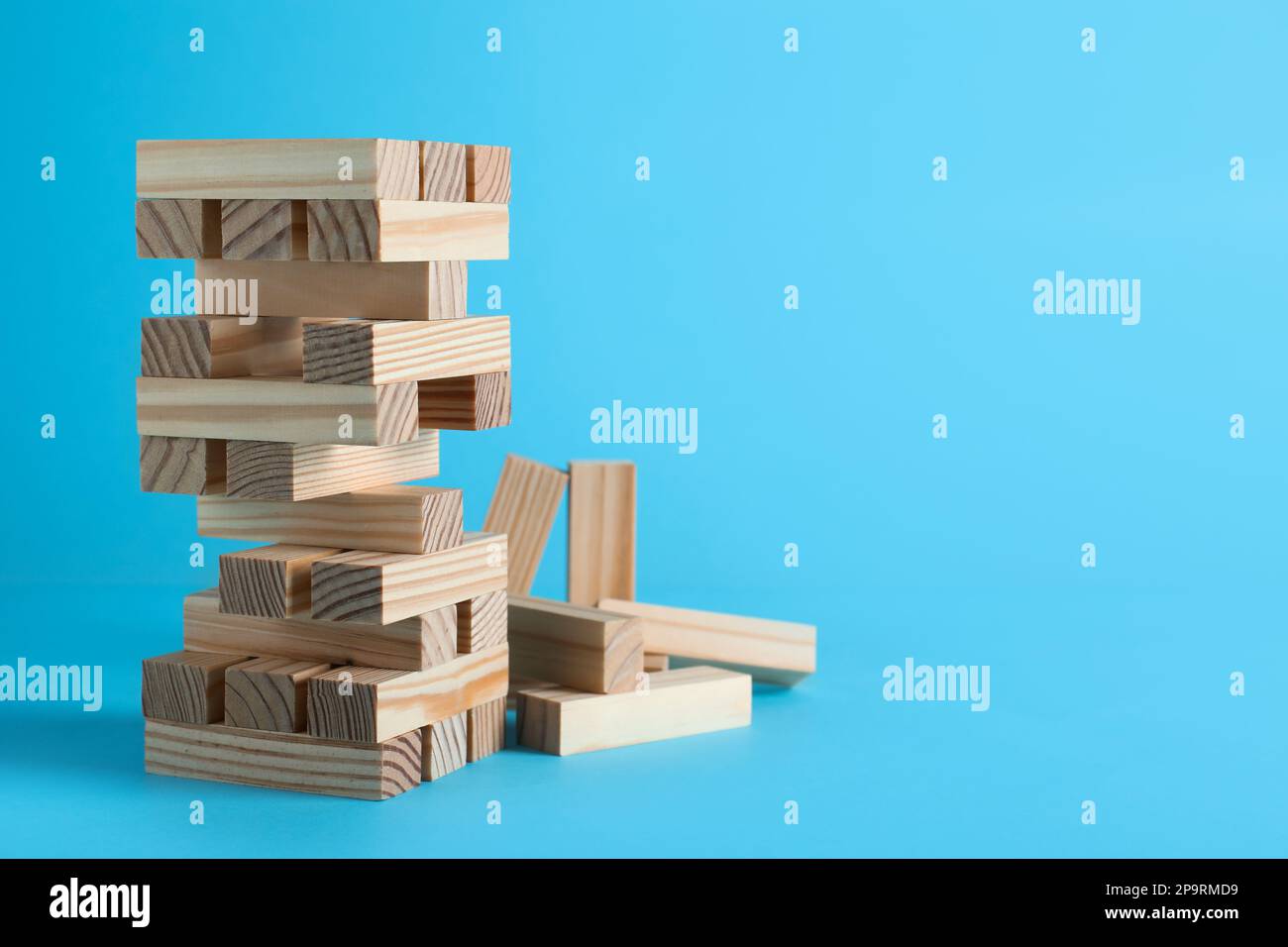 Jenga tower made of wooden blocks on light blue background, space for ...
