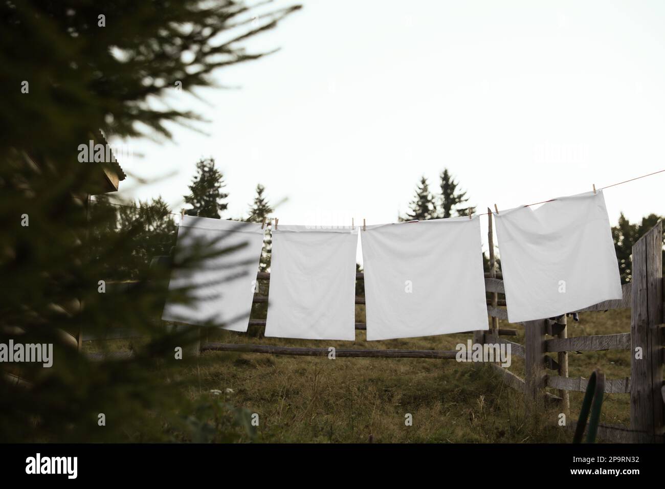 Bedclothes hanging on washing line near wooden fence outdoors Stock ...