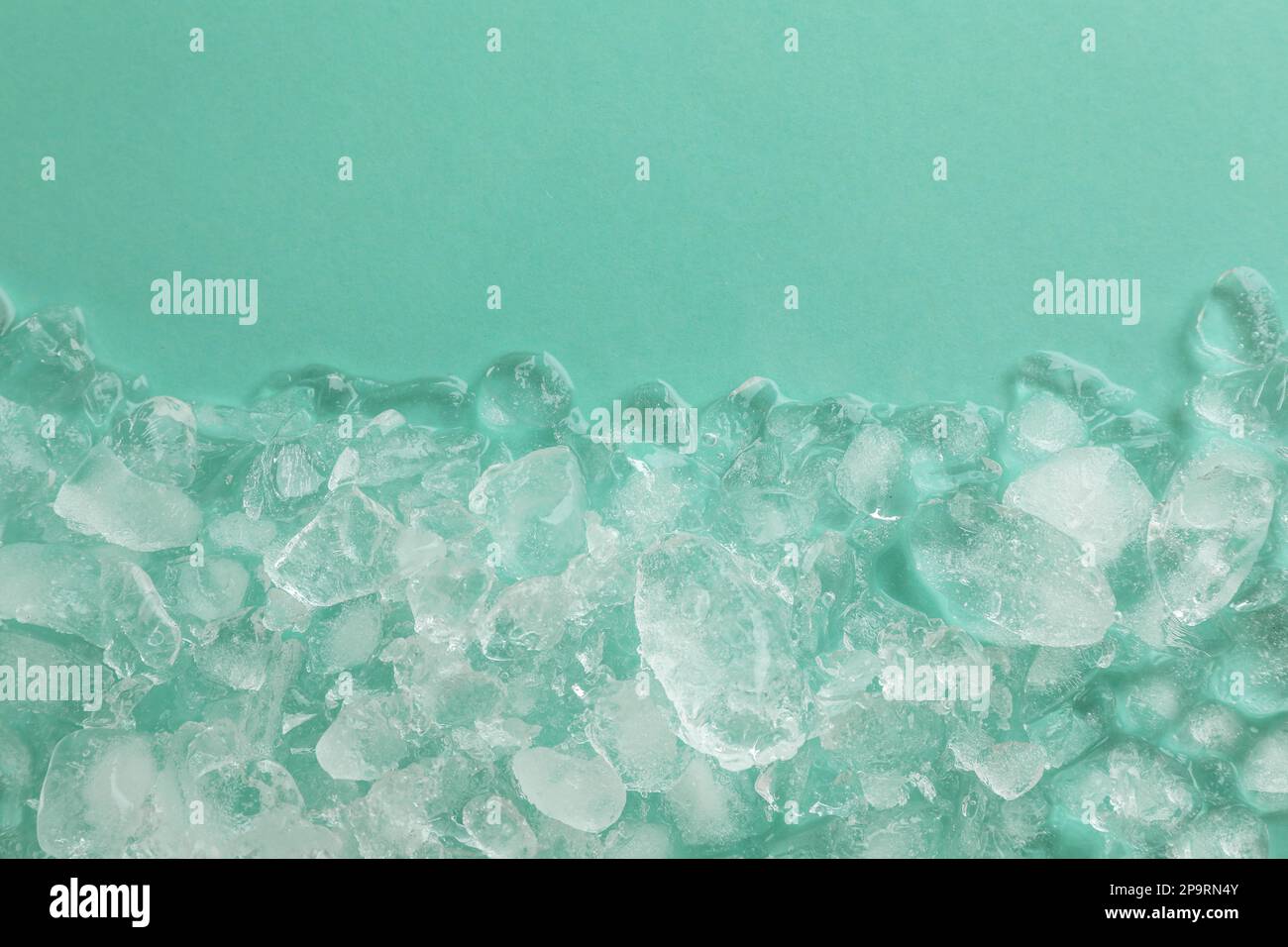 Pile of crushed ice on turquoise background, top view. Space for text ...