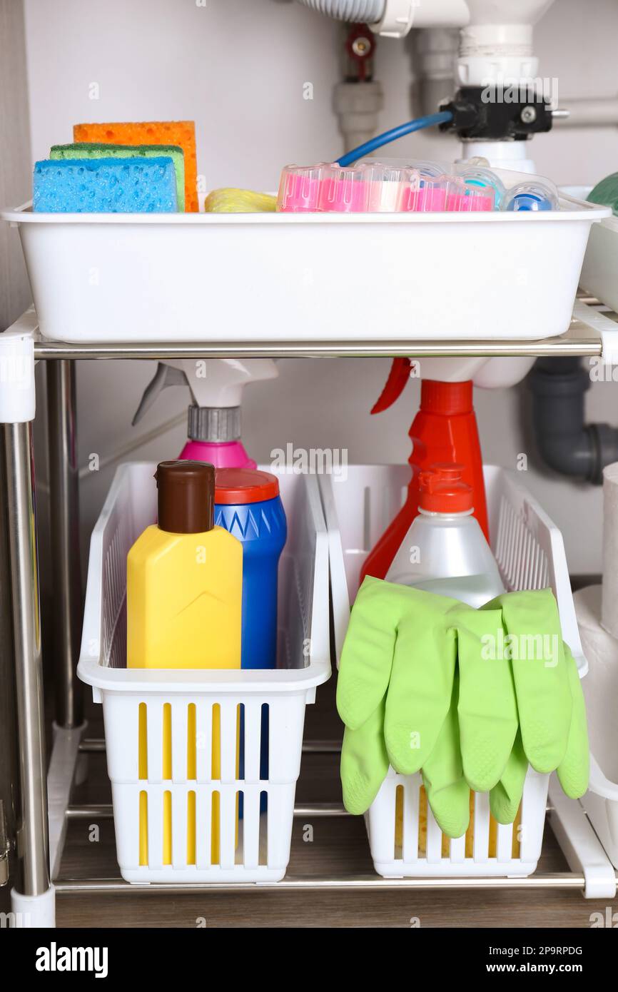 Open under sink cabinet with different cleaning supplies in kitchen ...