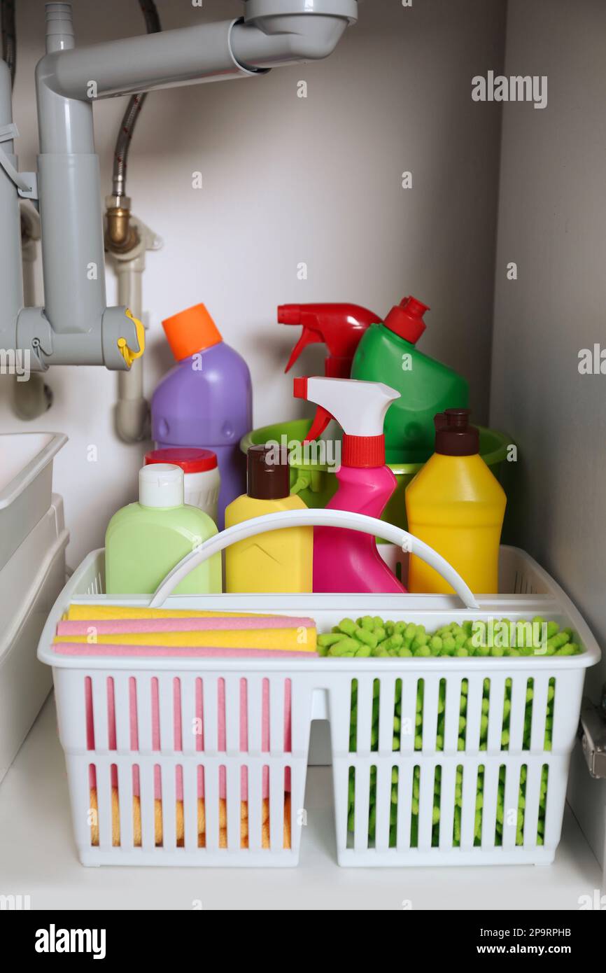 Open under sink cabinet with different cleaning supplies in kitchen ...