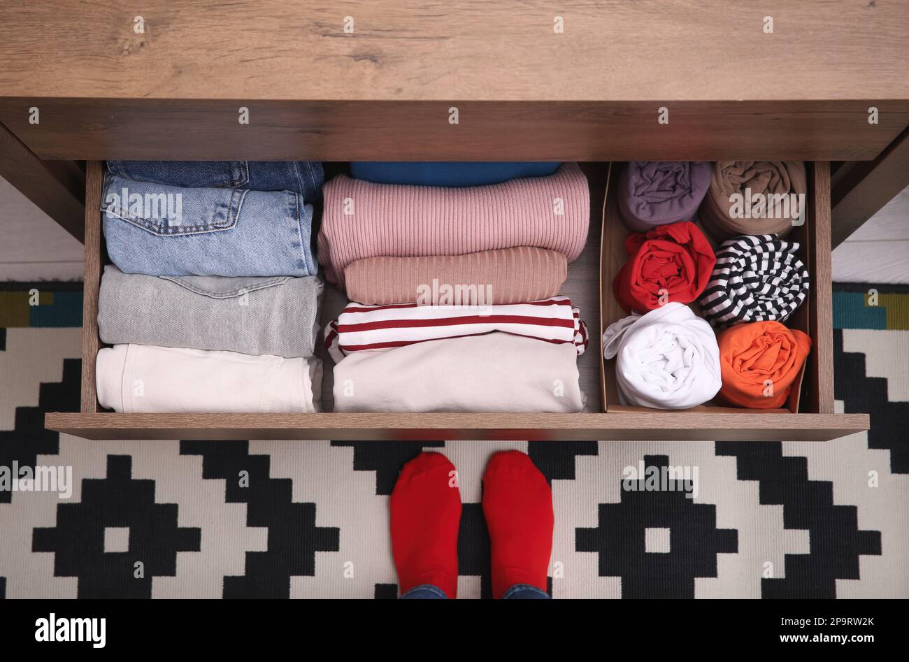 Woman near open drawer with folded clothes indoors, top view. Vertical ...