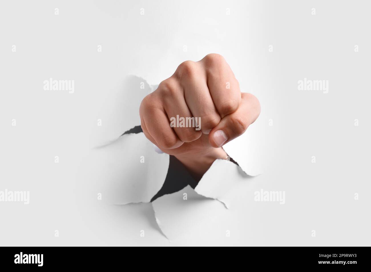 Man breaking through white paper with fist, closeup Stock Photo - Alamy