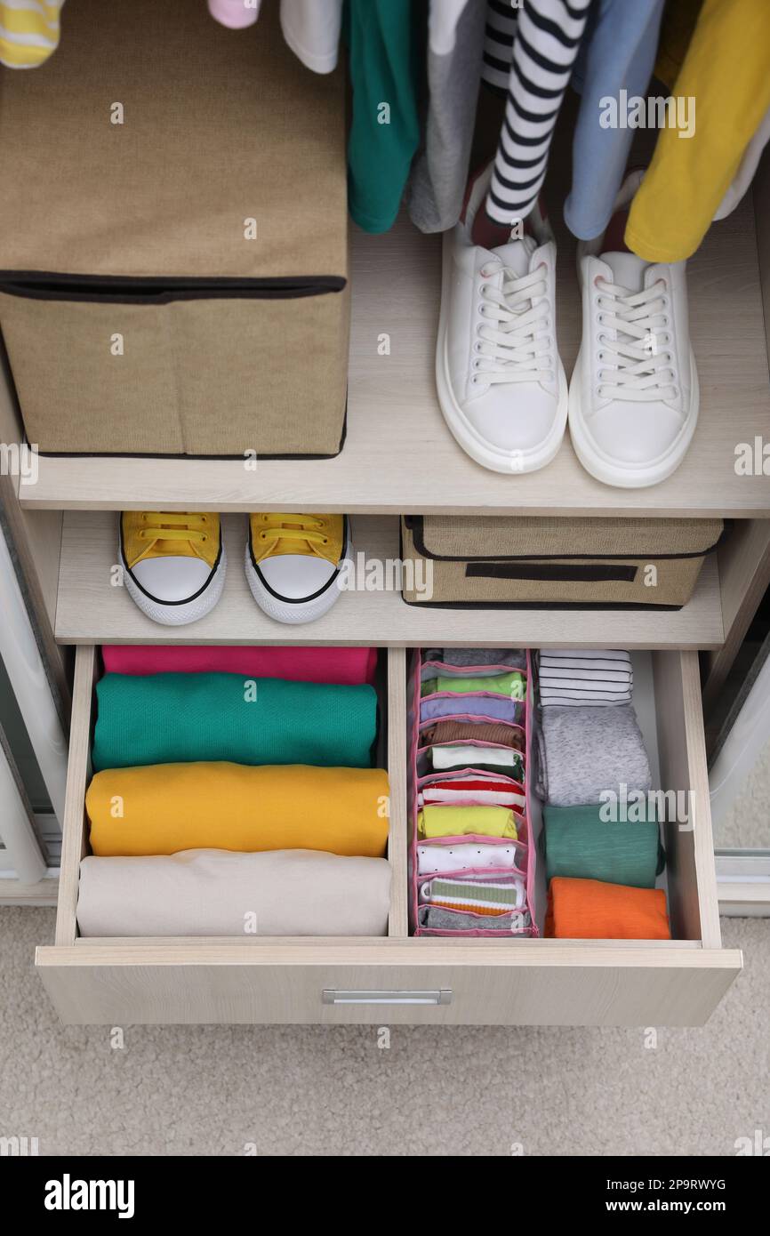Wardrobe with organized clothes and shoes indoors, above view. Vertical ...