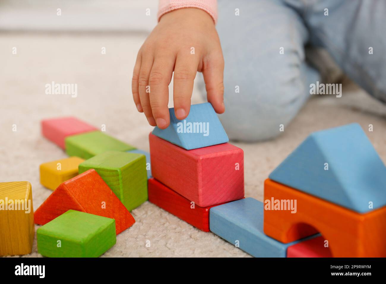 Cute little girl playing with colorful building blocks on floor ...