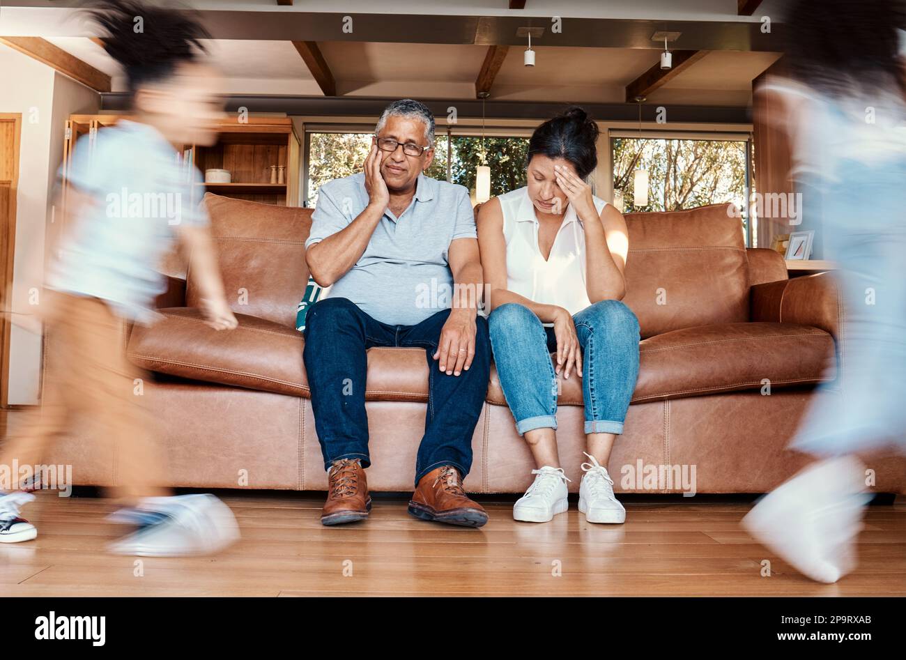 Kids running, stress and grandparents on couch tired, chaos in living ...